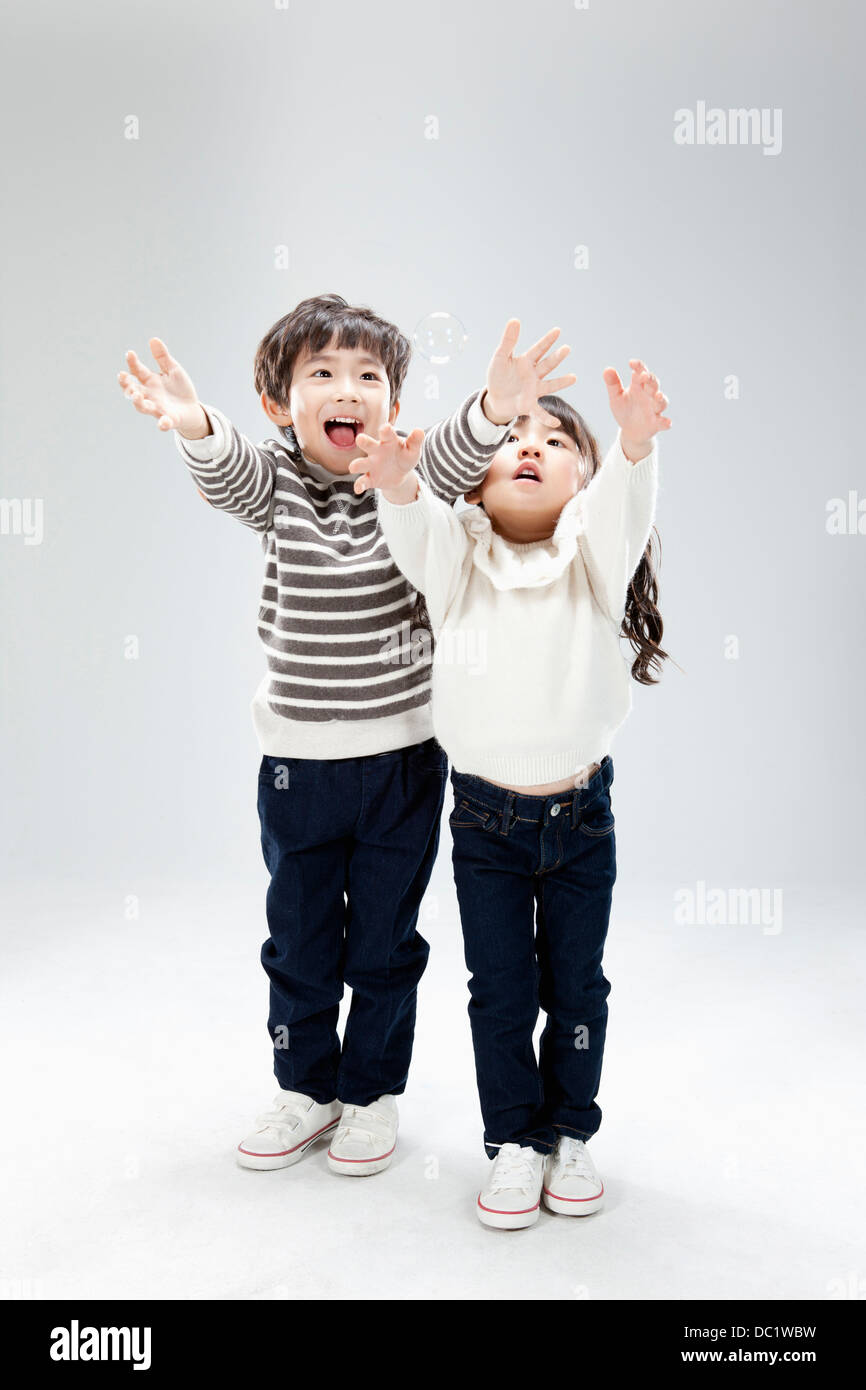 a boy and a girl trying to reach something Stock Photo - Alamy