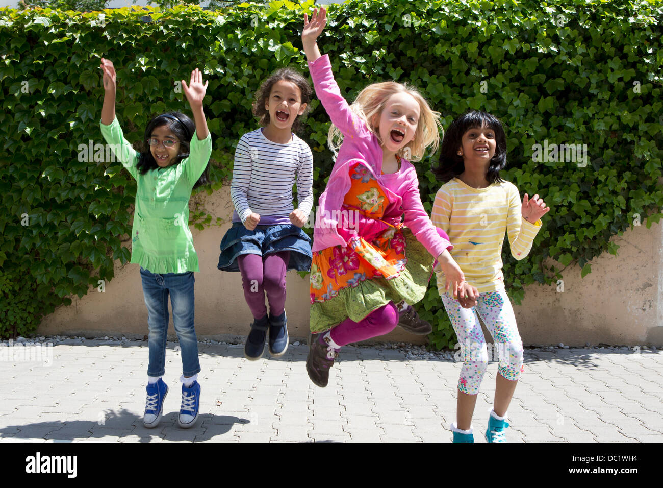Four girls jumping in garden Stock Photo - Alamy