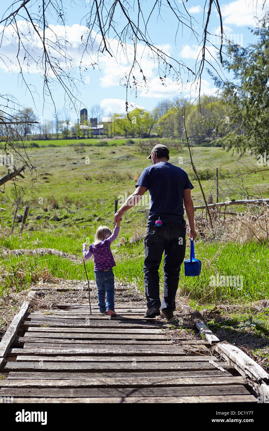 Father and daughter holding hands and walking over wooden bridge Stock ...