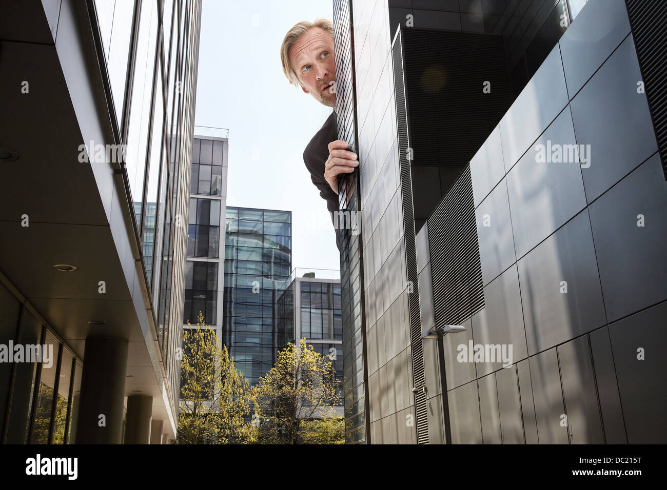 Oversized businessman peering from behind skyscrapers, low angle view ...