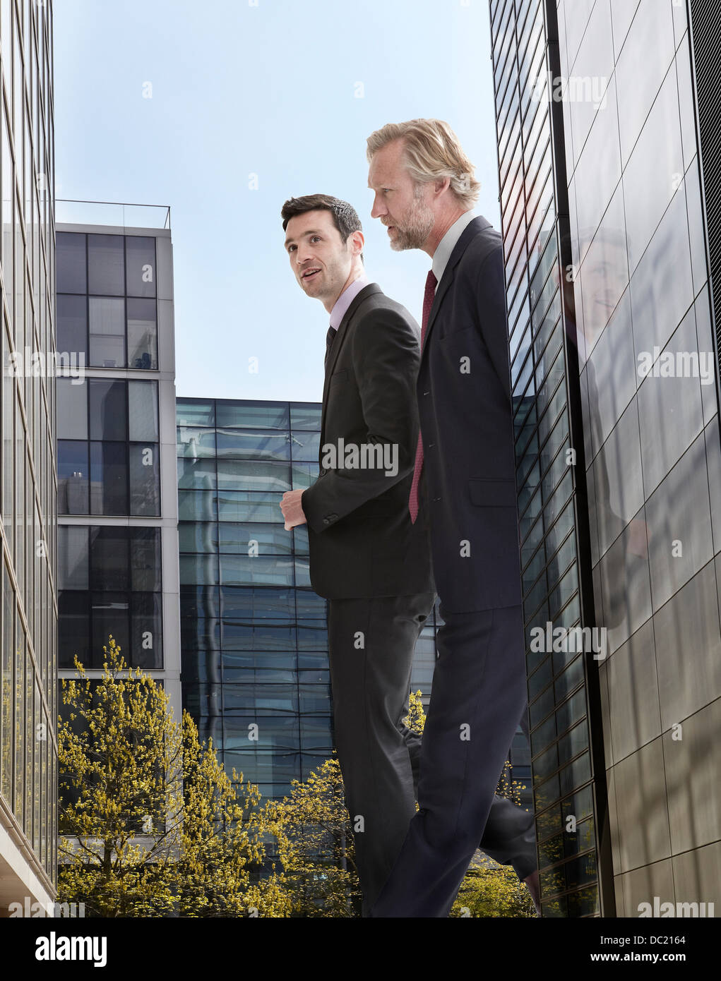 Oversized businessmen walking amongst skyscrapers, low angle view Stock ...