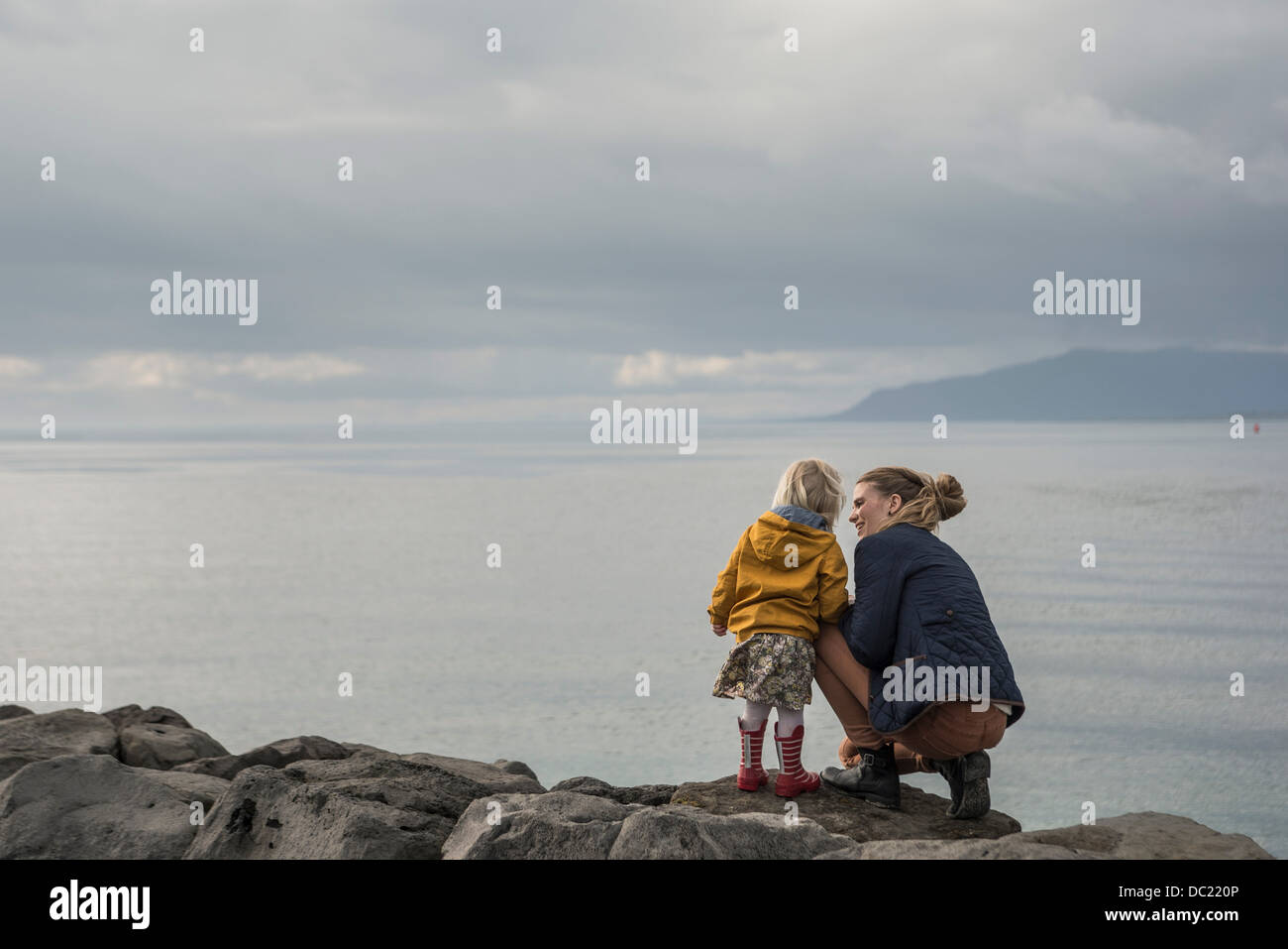 Mother and toddler crouching on harbor wall Stock Photo - Alamy