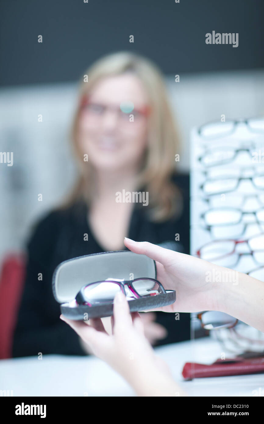 Shop assistant showing customer glasses in opticians shop Stock Photo ...