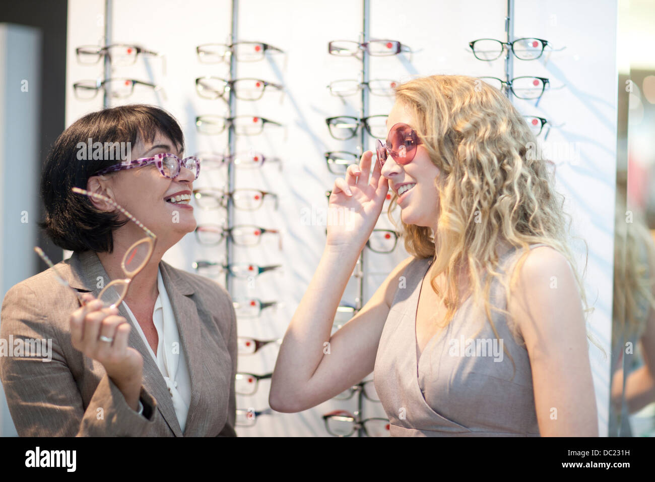 Two women trying on eyeglasses in opticians shop Stock Photo - Alamy