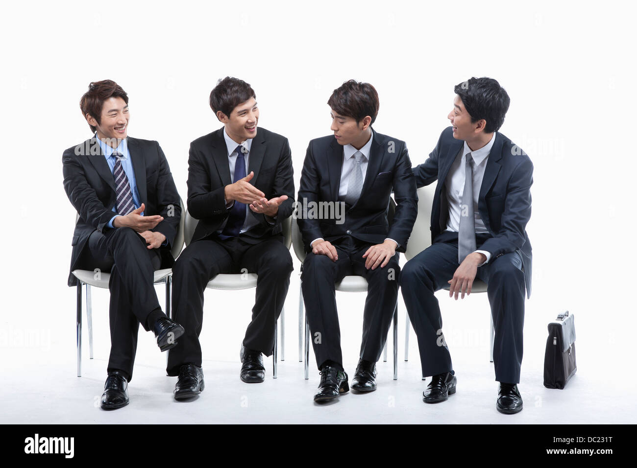 businessmen sitting on chairs in a line talking to each other Stock ...