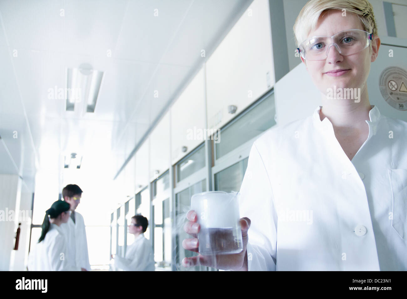 Chemistry student holding beaker of liquid in laboratory, portrait ...