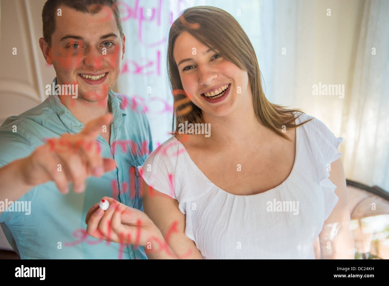 Couple writing list of names on glass Stock Photo - Alamy