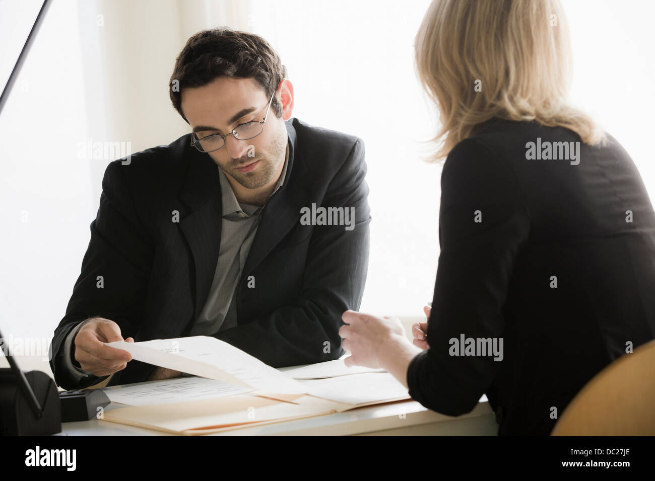 Young office workers looking through paperwork Stock Photo - Alamy