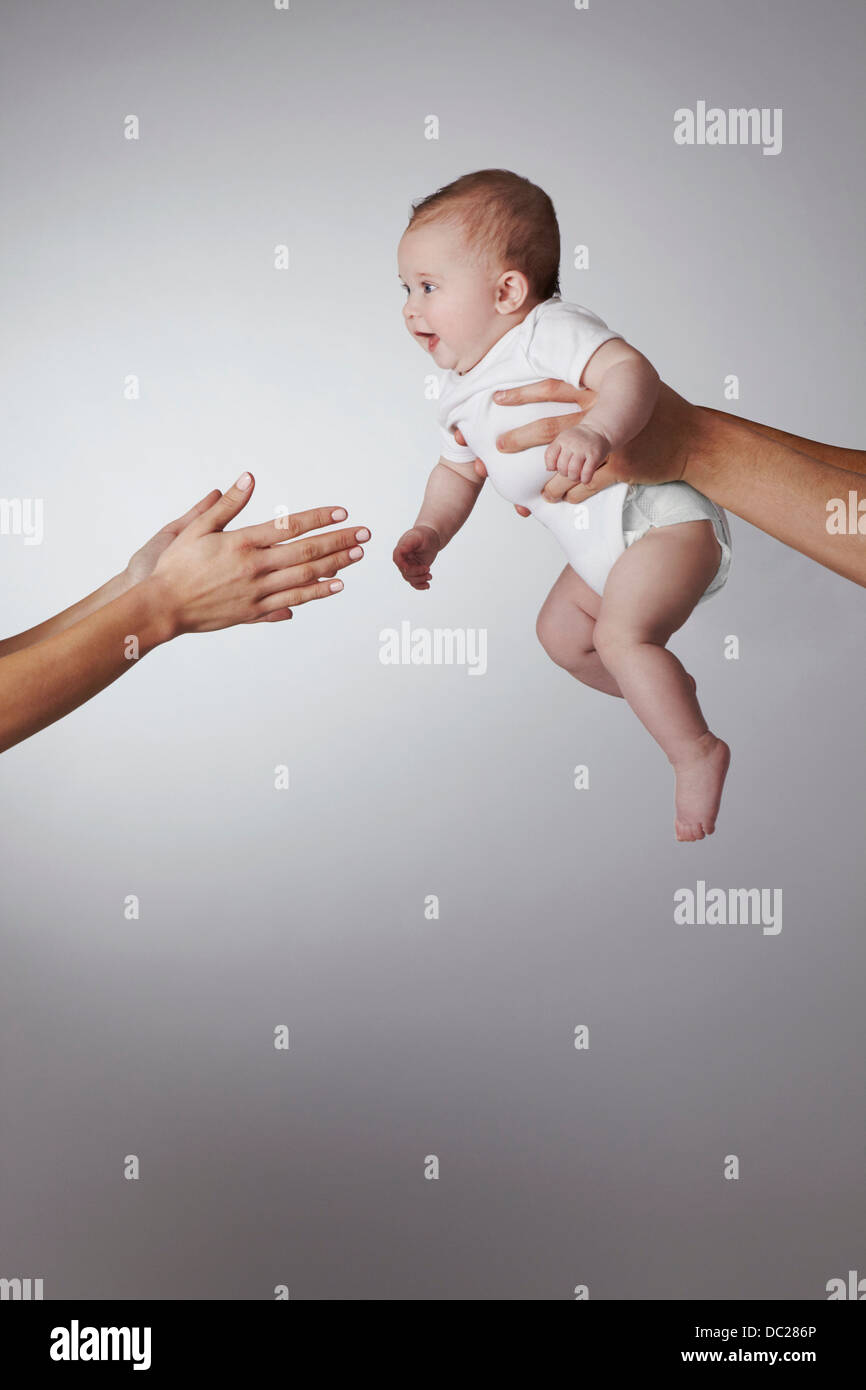 Parents passing baby daughter to each other Stock Photo - Alamy