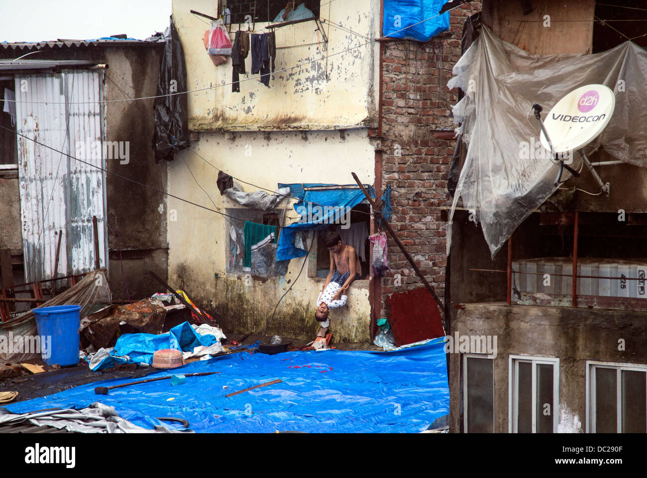 Slum buildings life children playing hanging out of window held by legs ...