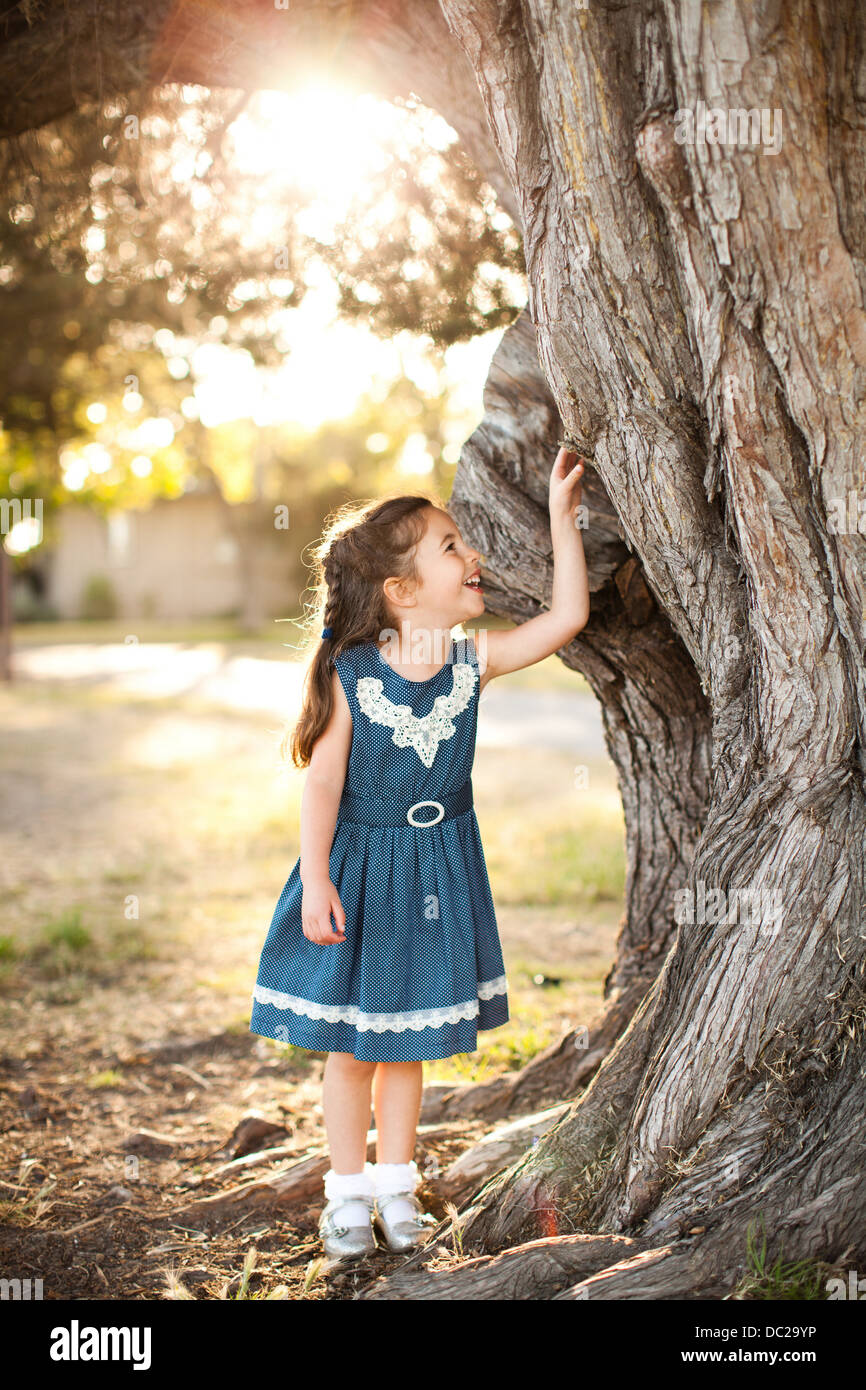 Portrait of girl touching tree trunk Stock Photo - Alamy