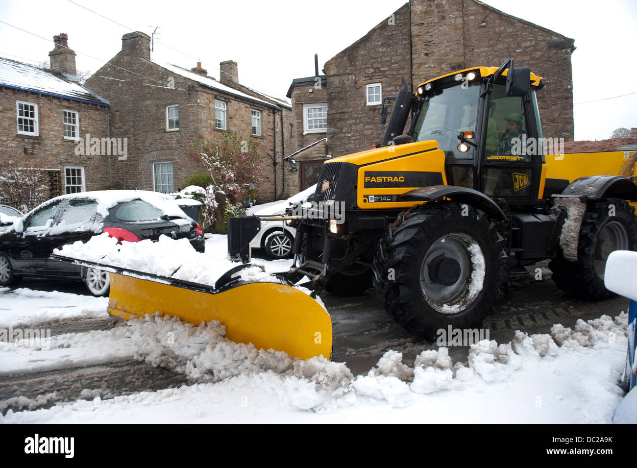A tractor with a grit spreading machine fitted drives through a small ...