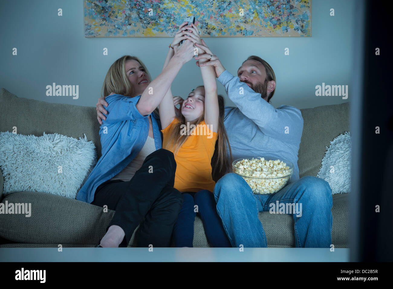Parents and child fighting for remote control Stock Photo - Alamy