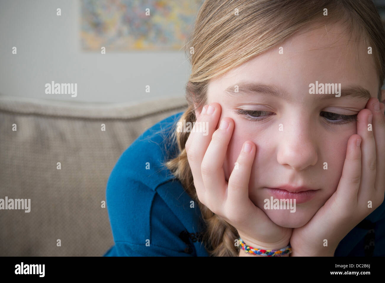 Girl with hands on face looking down Stock Photo - Alamy
