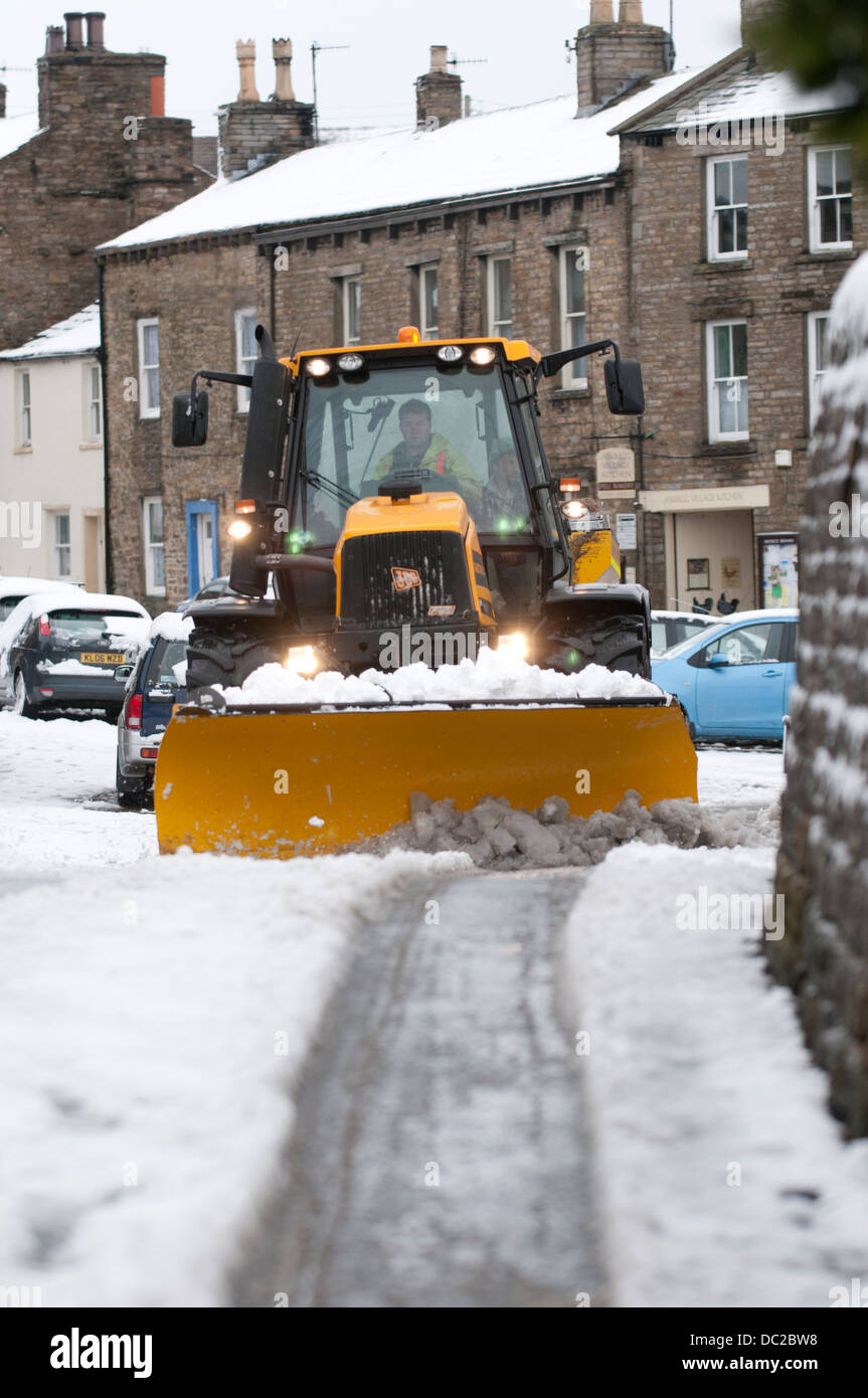 A tractor with a grit spreading machine fitted drives through a small ...