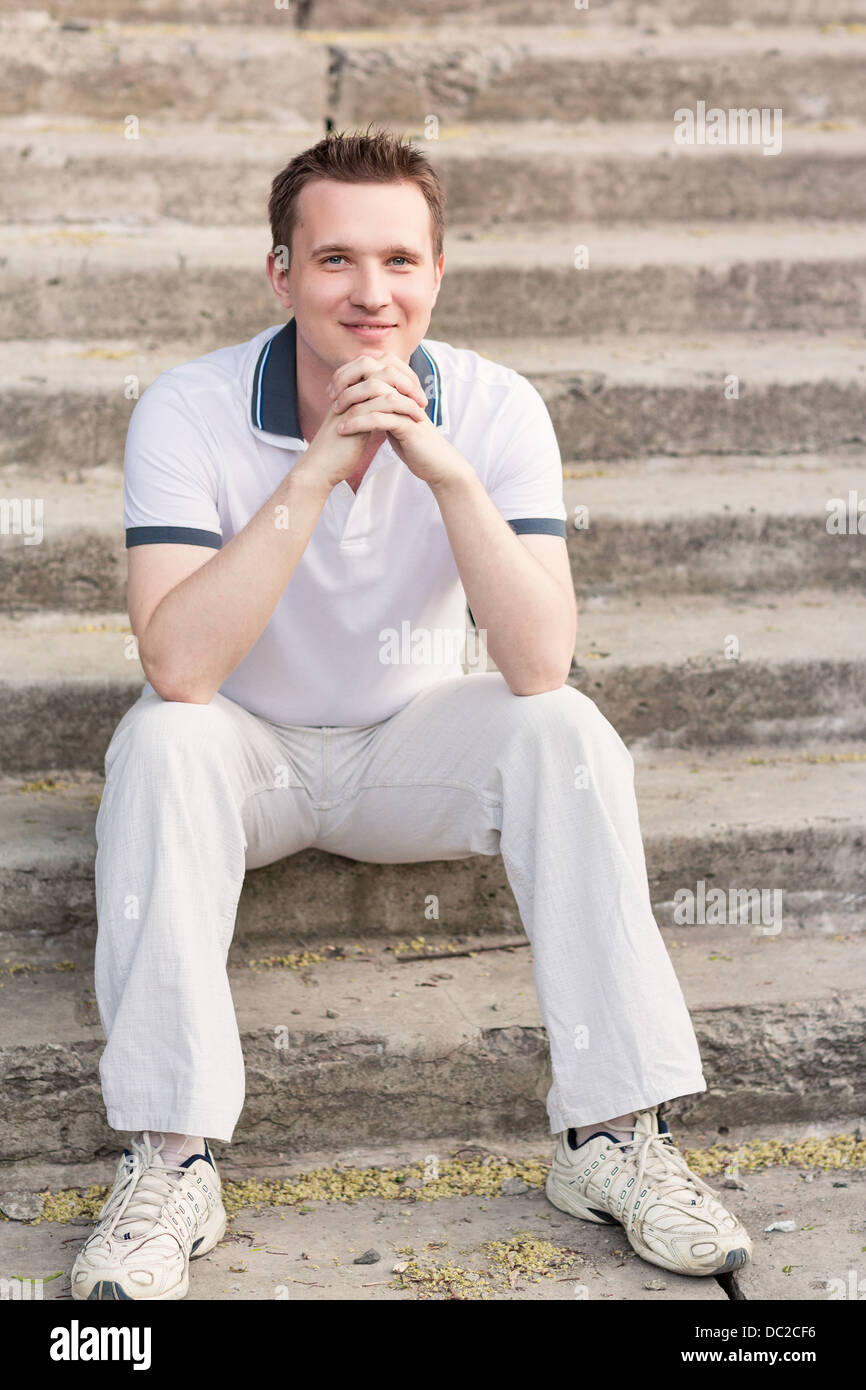 Young man sitting on stairs outdoor Stock Photo - Alamy