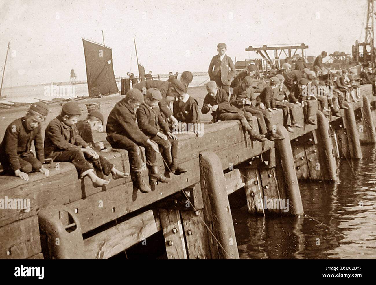 Boys fishing on a pier early 1900s Stock Photo - Alamy