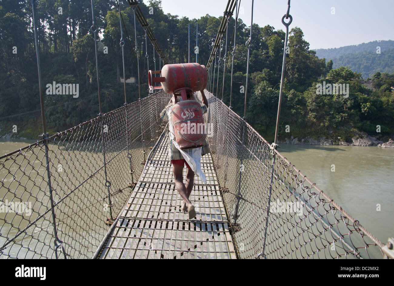 Cooking gas delivery man negotiates a suspension bridge over the ...