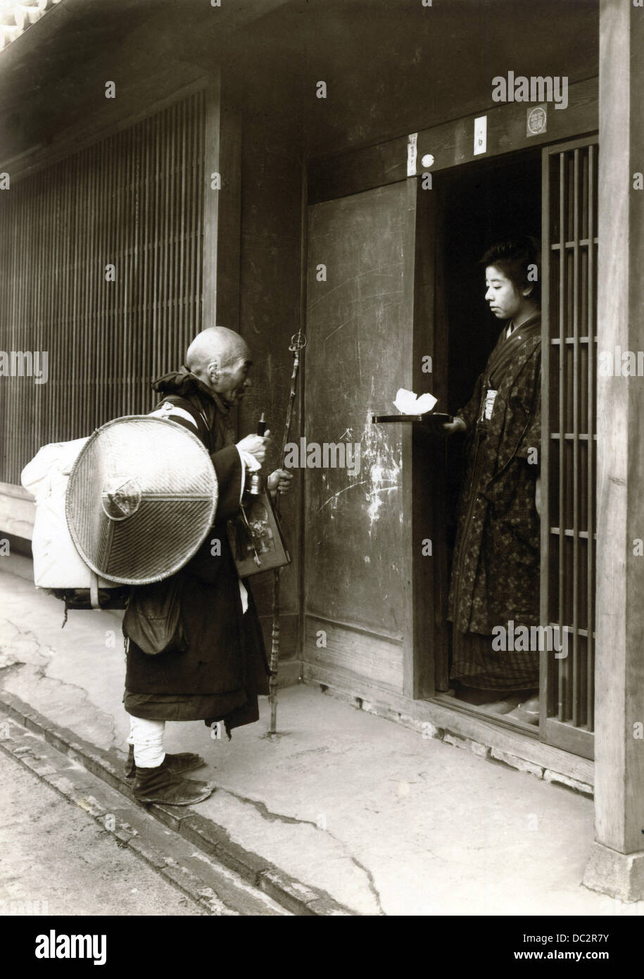 A medicant receives a bowl of tea. Pictured in the early 1920th Stock ...