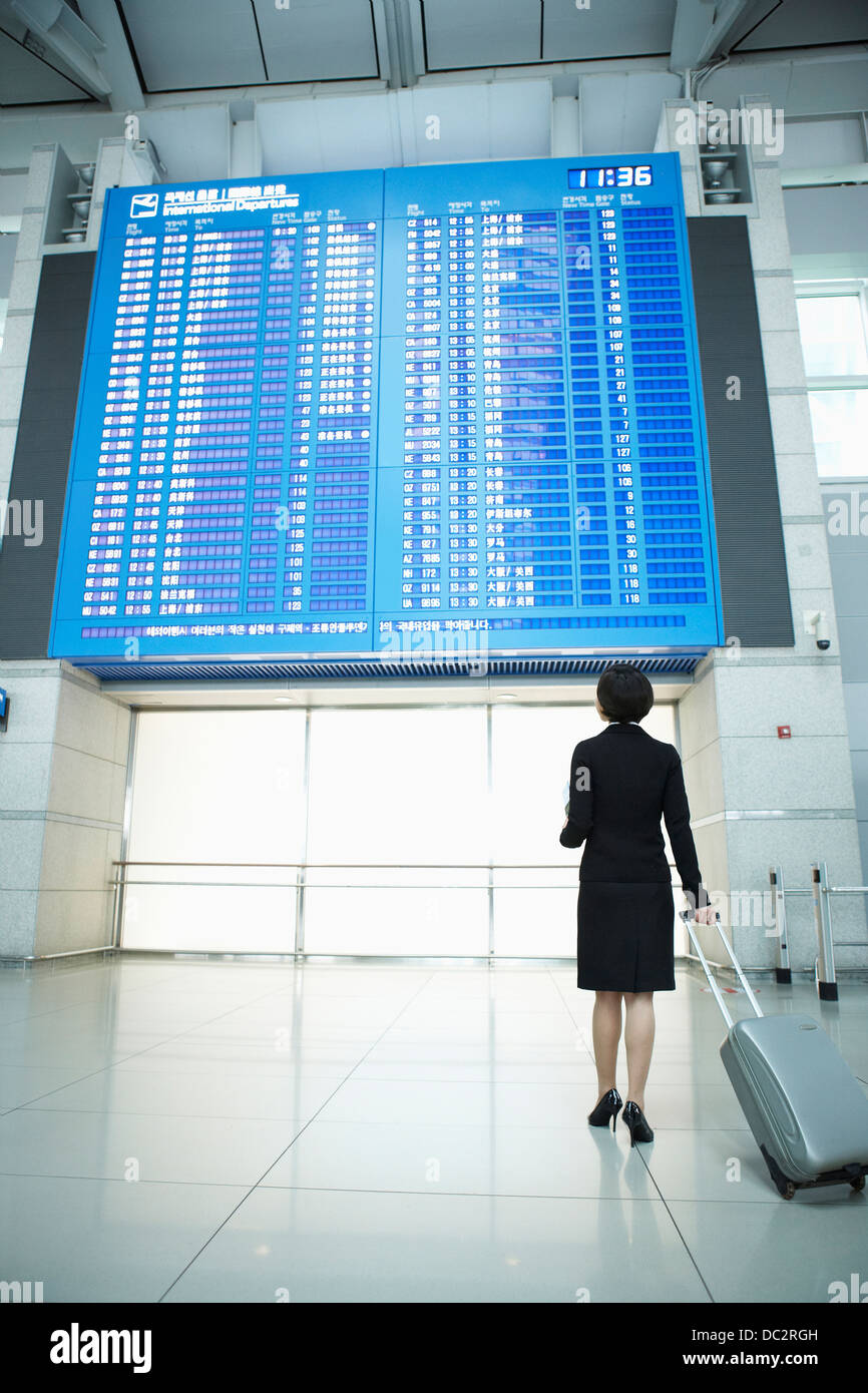 a businesswoman checking departure timetable at airport Stock Photo - Alamy