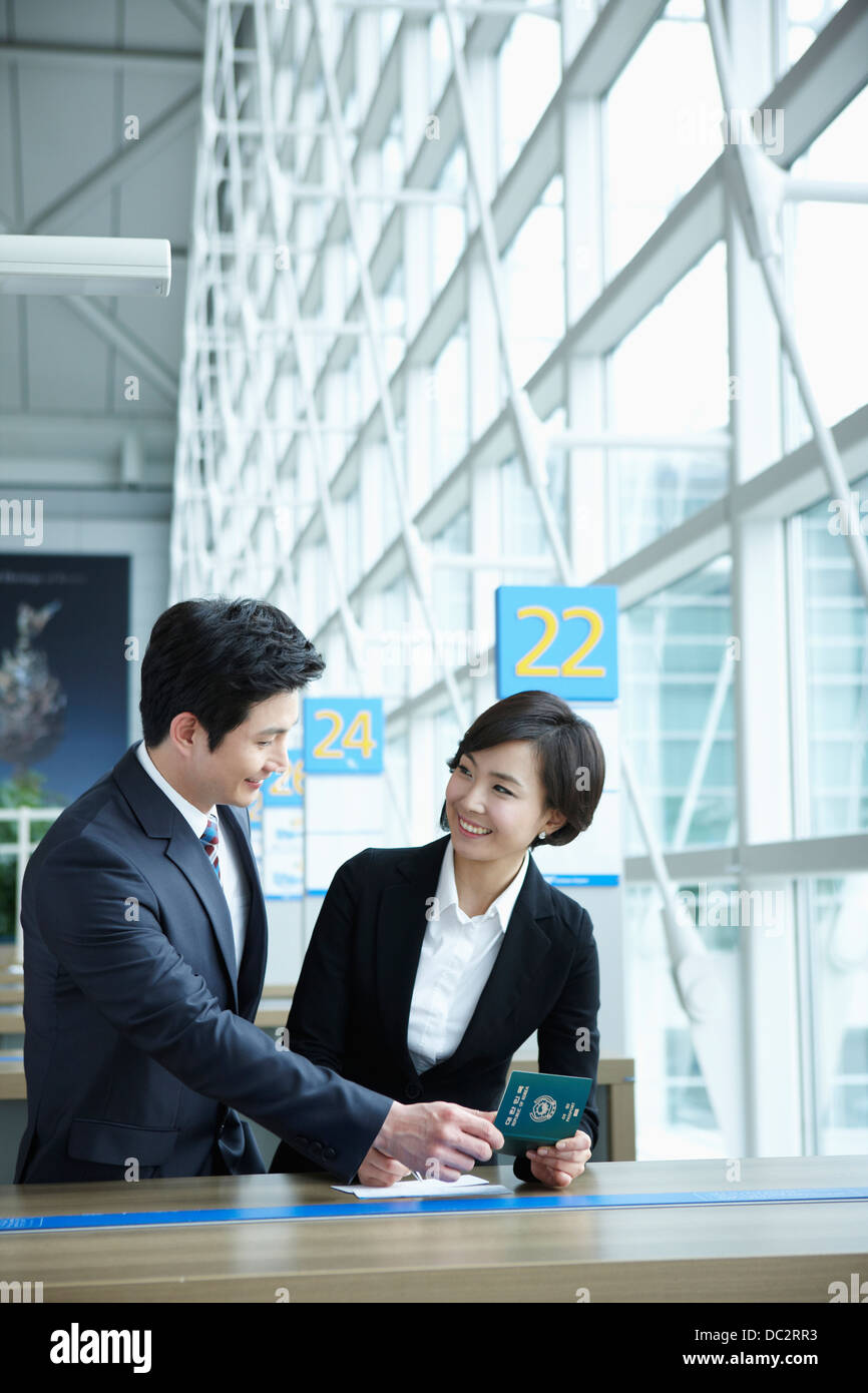 a businessman helping woman write trip information at airport Stock ...