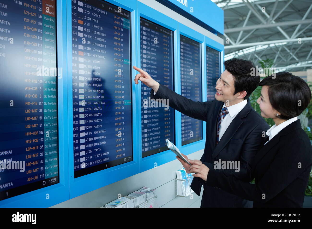a businessman and woman checking departure timetable at airport Stock ...