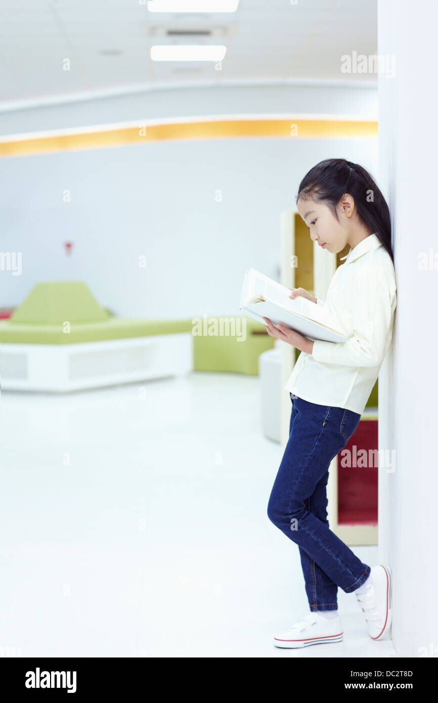 a girl reading a book leaning on a wall Stock Photo - Alamy