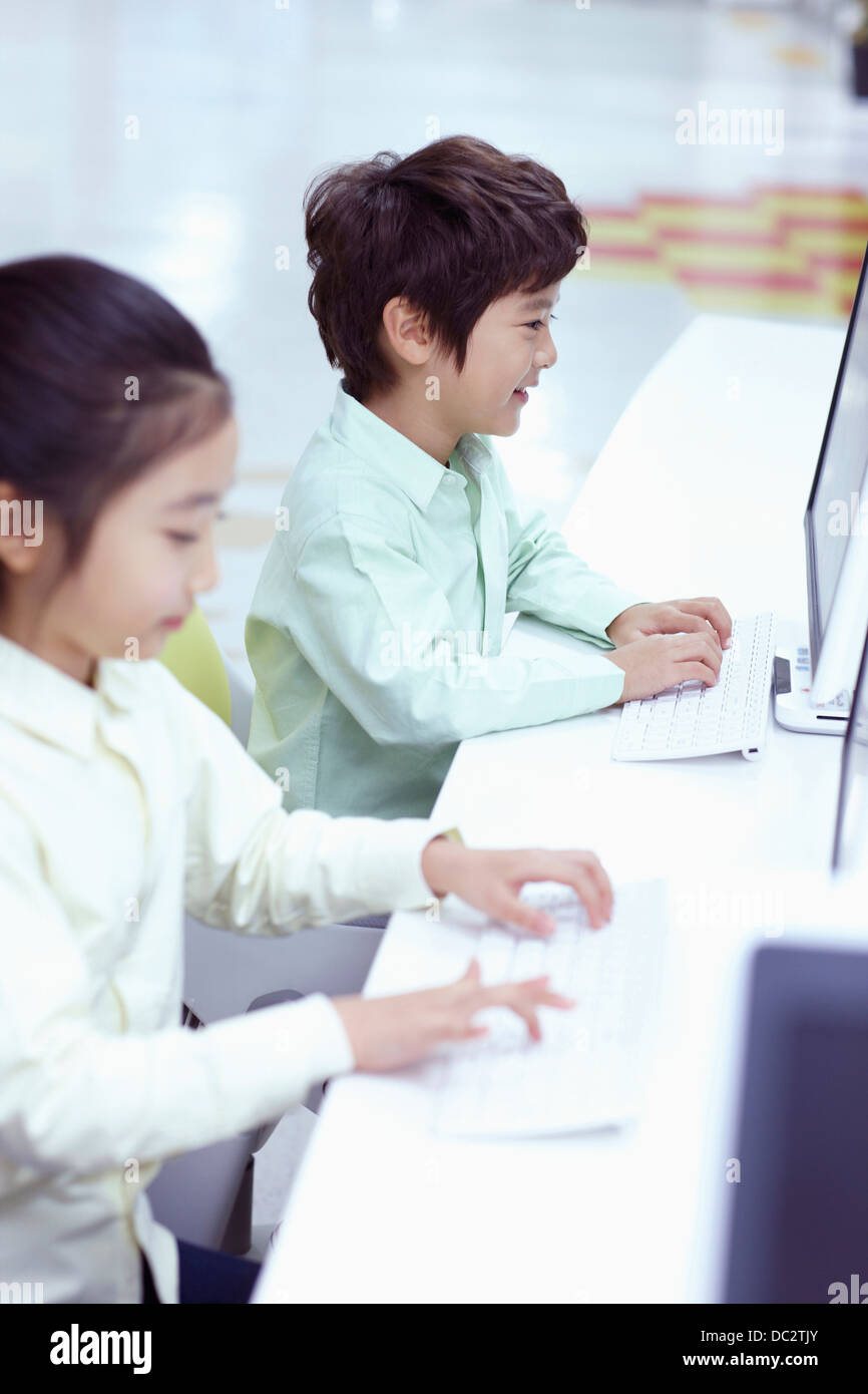 a boy and a girl using each PC Stock Photo - Alamy