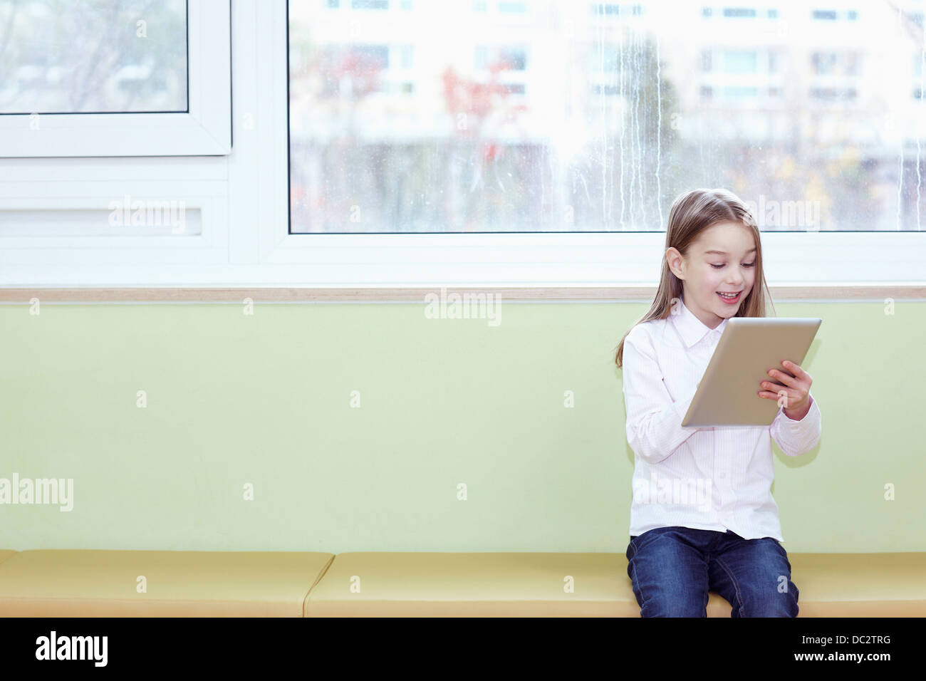 a girl using tablet PC while sitting Stock Photo - Alamy