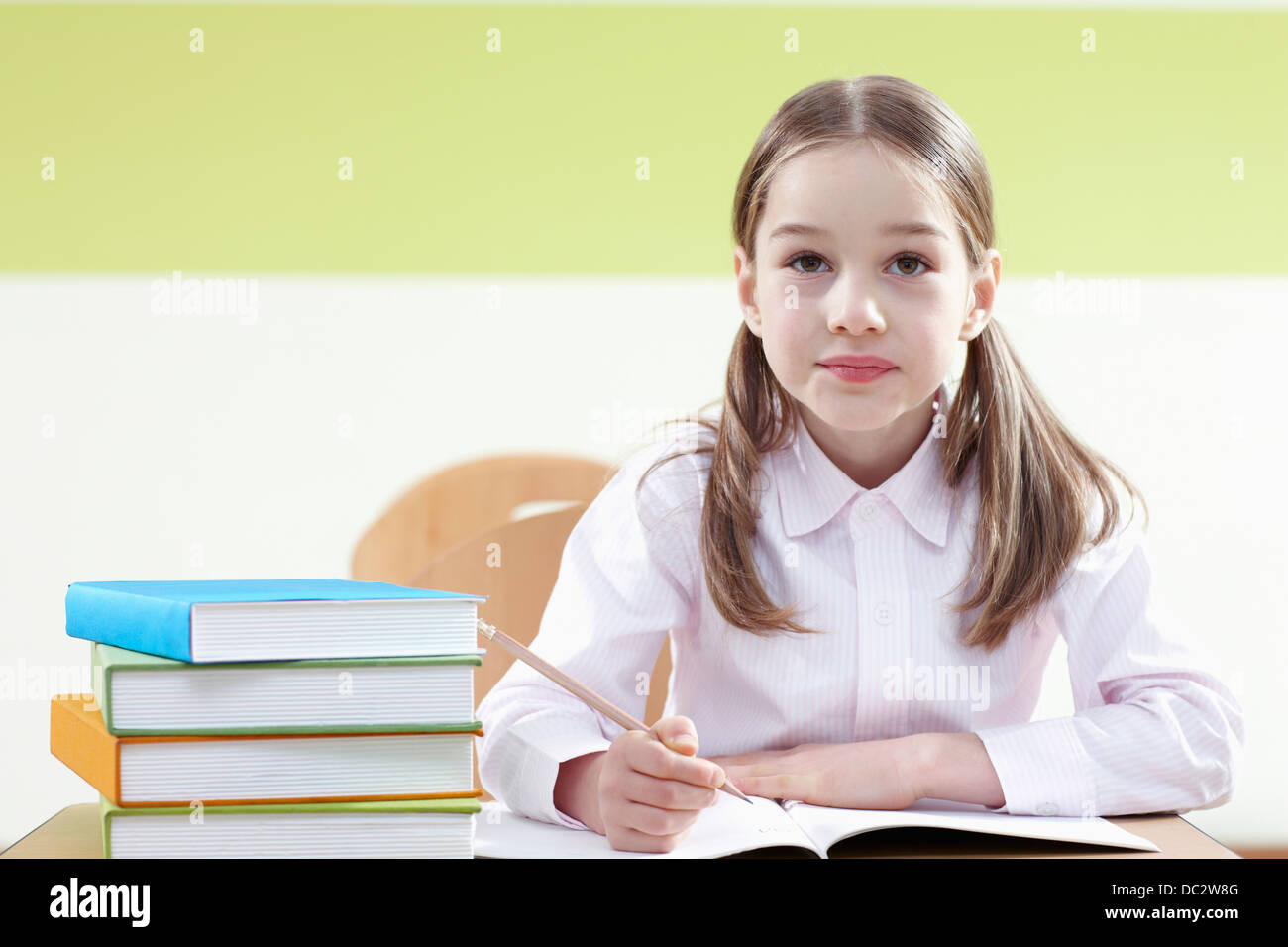 a girl sitting at a desk in a classroom studying Stock Photo - Alamy