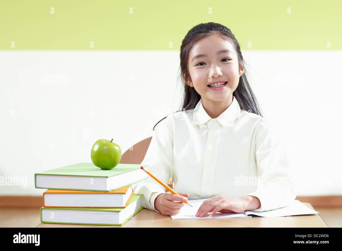 a girl sitting at a desk in a classroom studying Stock Photo - Alamy