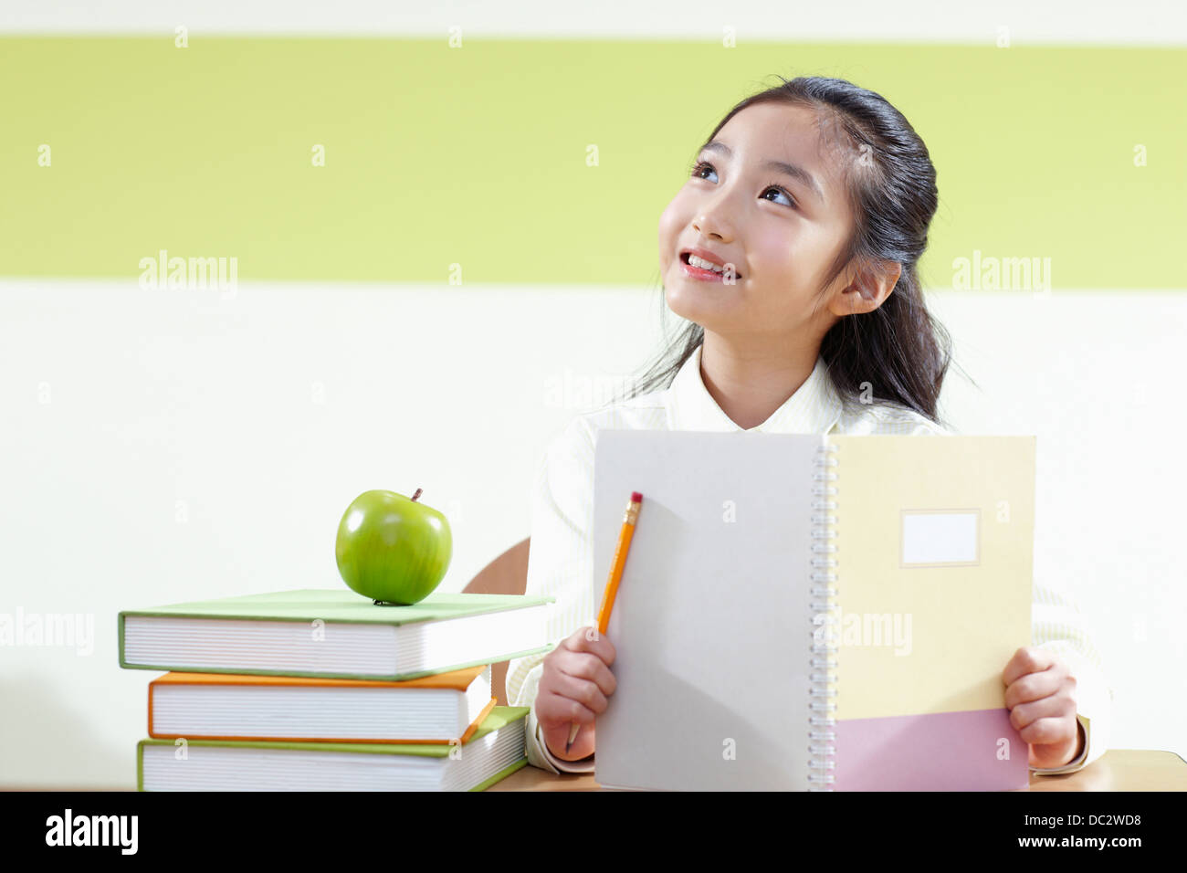 a girl sitting at a desk in a classroom reading a notebook Stock Photo ...