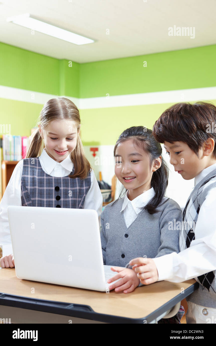 kids using a laptop together in a classroom Stock Photo - Alamy