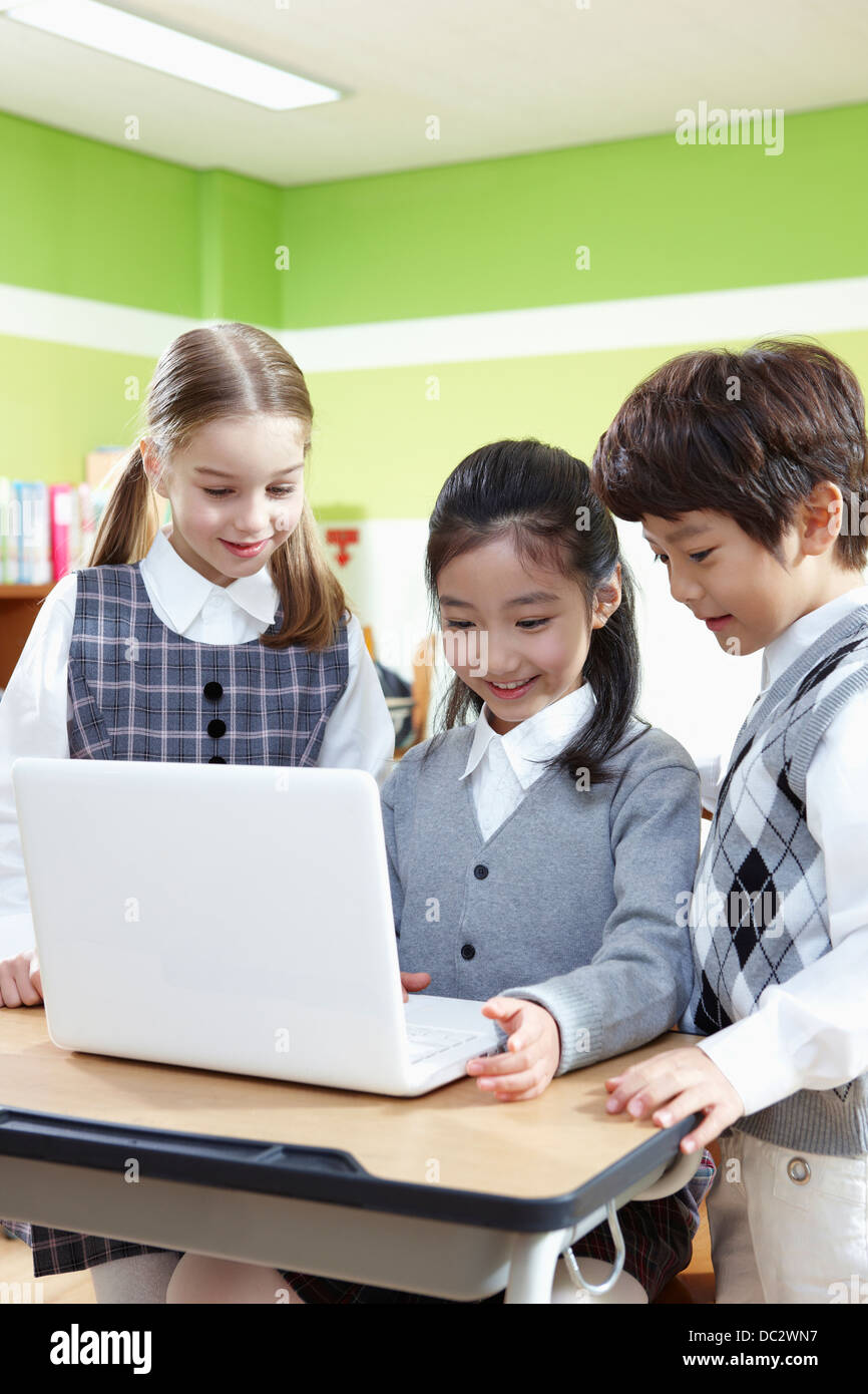 kids using a laptop together in a classroom Stock Photo - Alamy