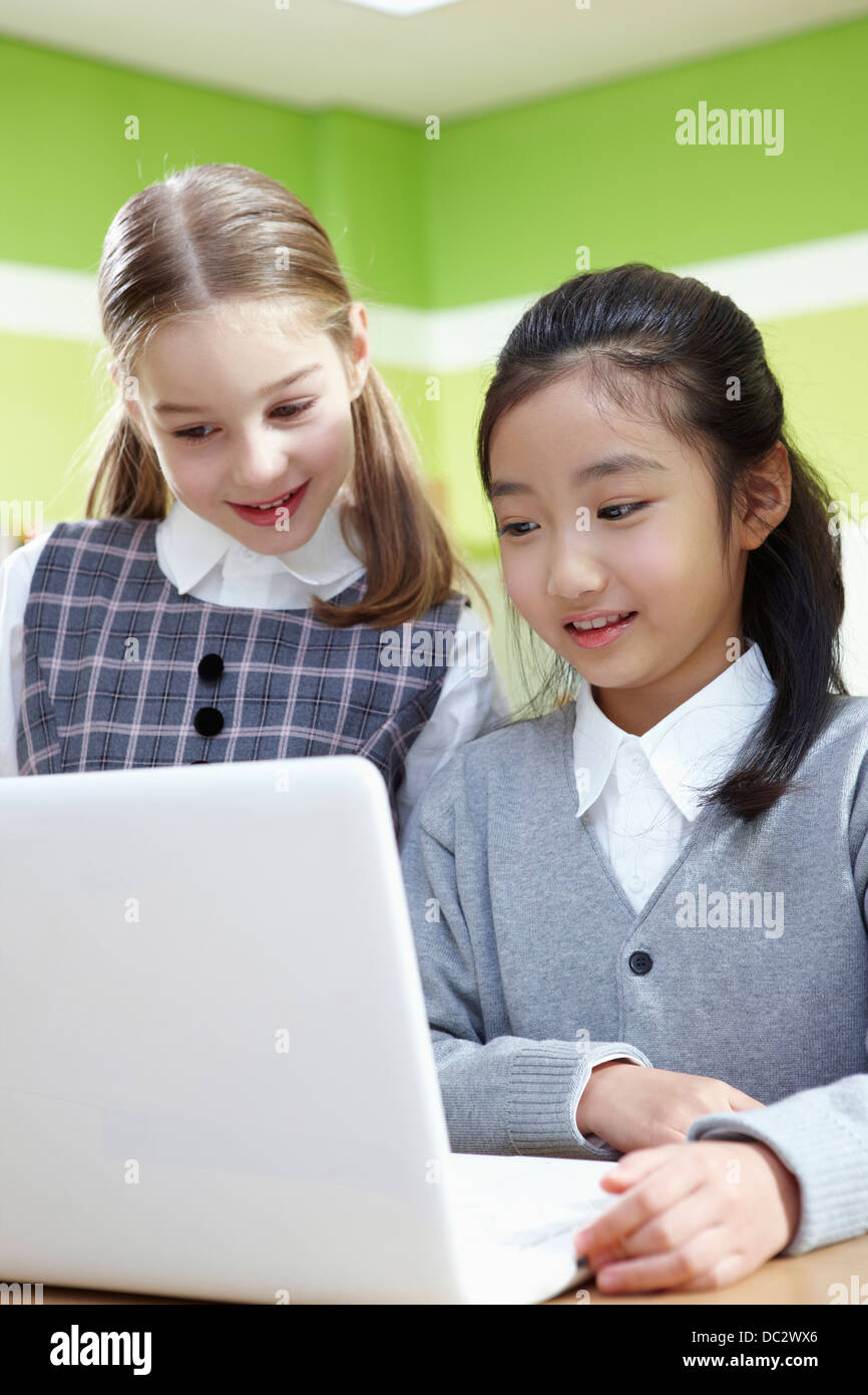 girls using a laptop together in a classroom Stock Photo - Alamy
