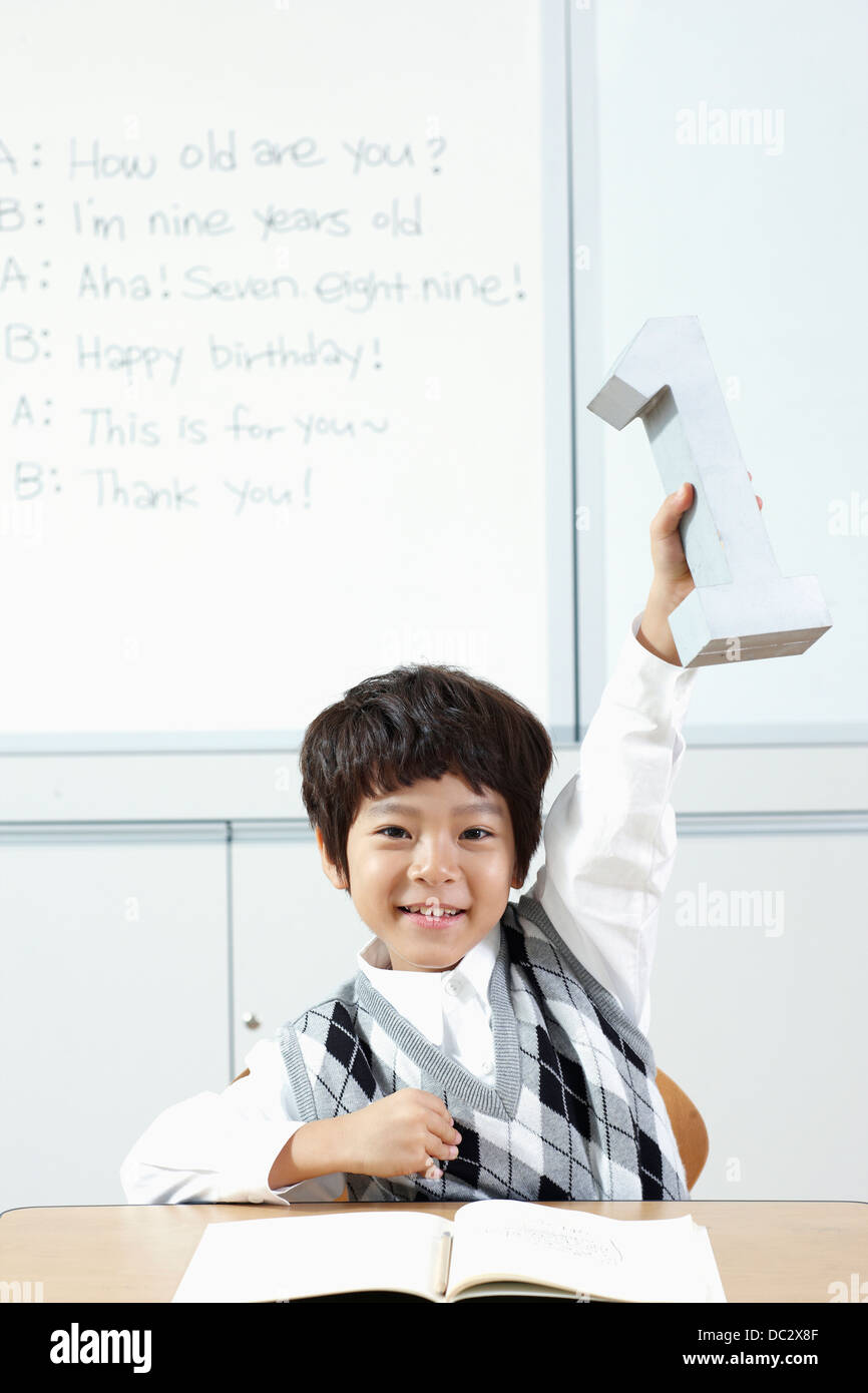 a boy holding up number one sign in a classroom Stock Photo - Alamy