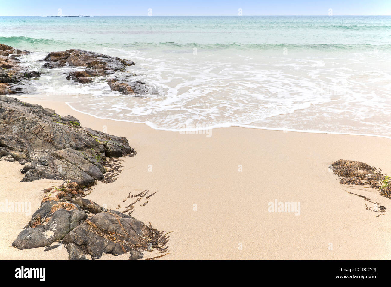 Beautiful yellow sand beach with emerald ocean and rocks Stock Photo ...
