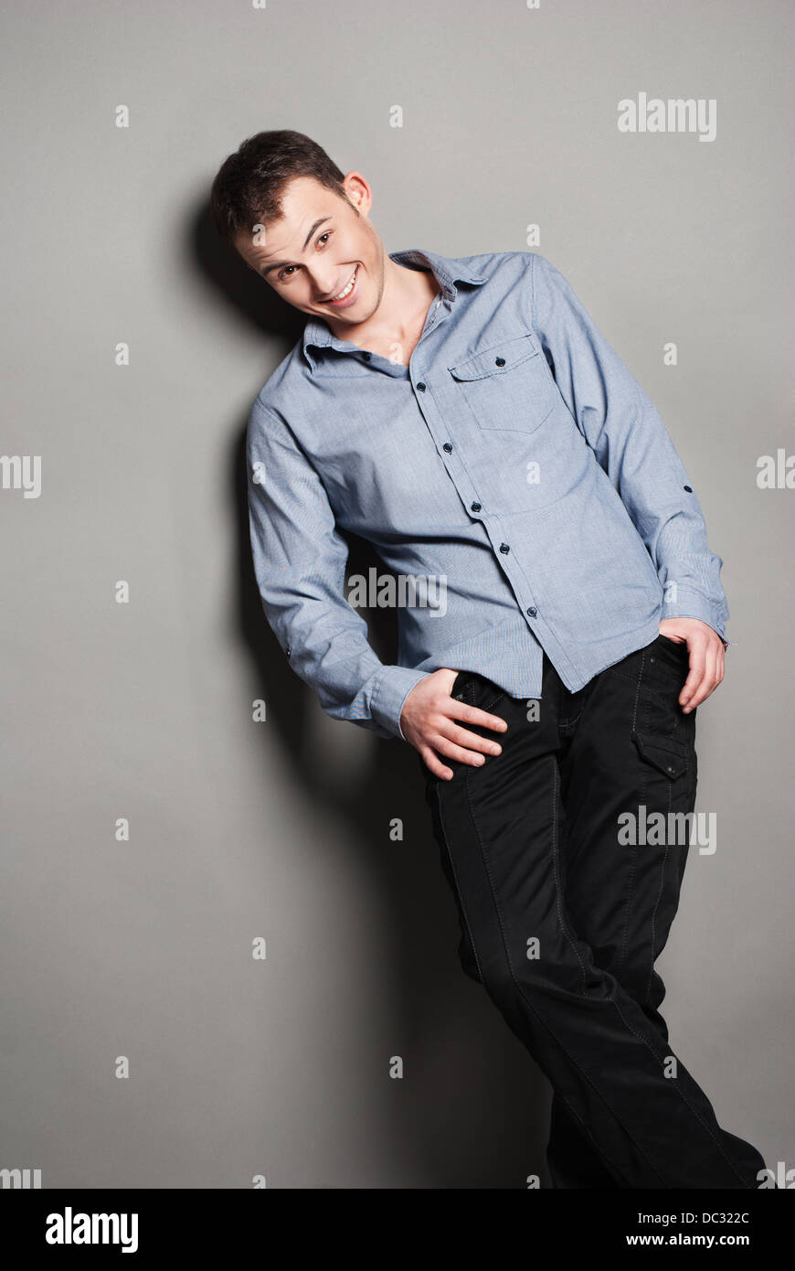 Handsome smiling man casually leaning against the wall Stock Photo - Alamy