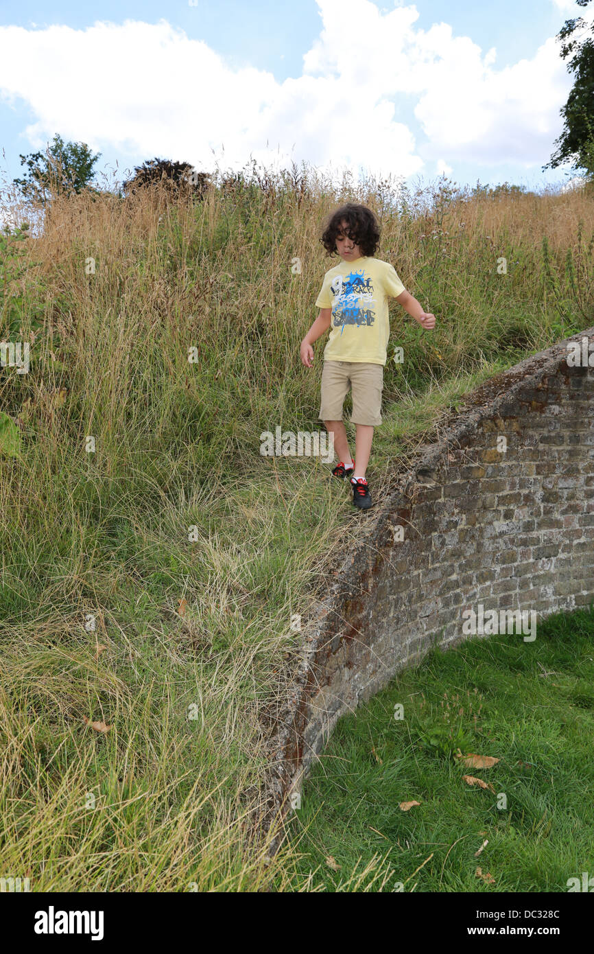 Young boy walking on a wall Stock Photo - Alamy