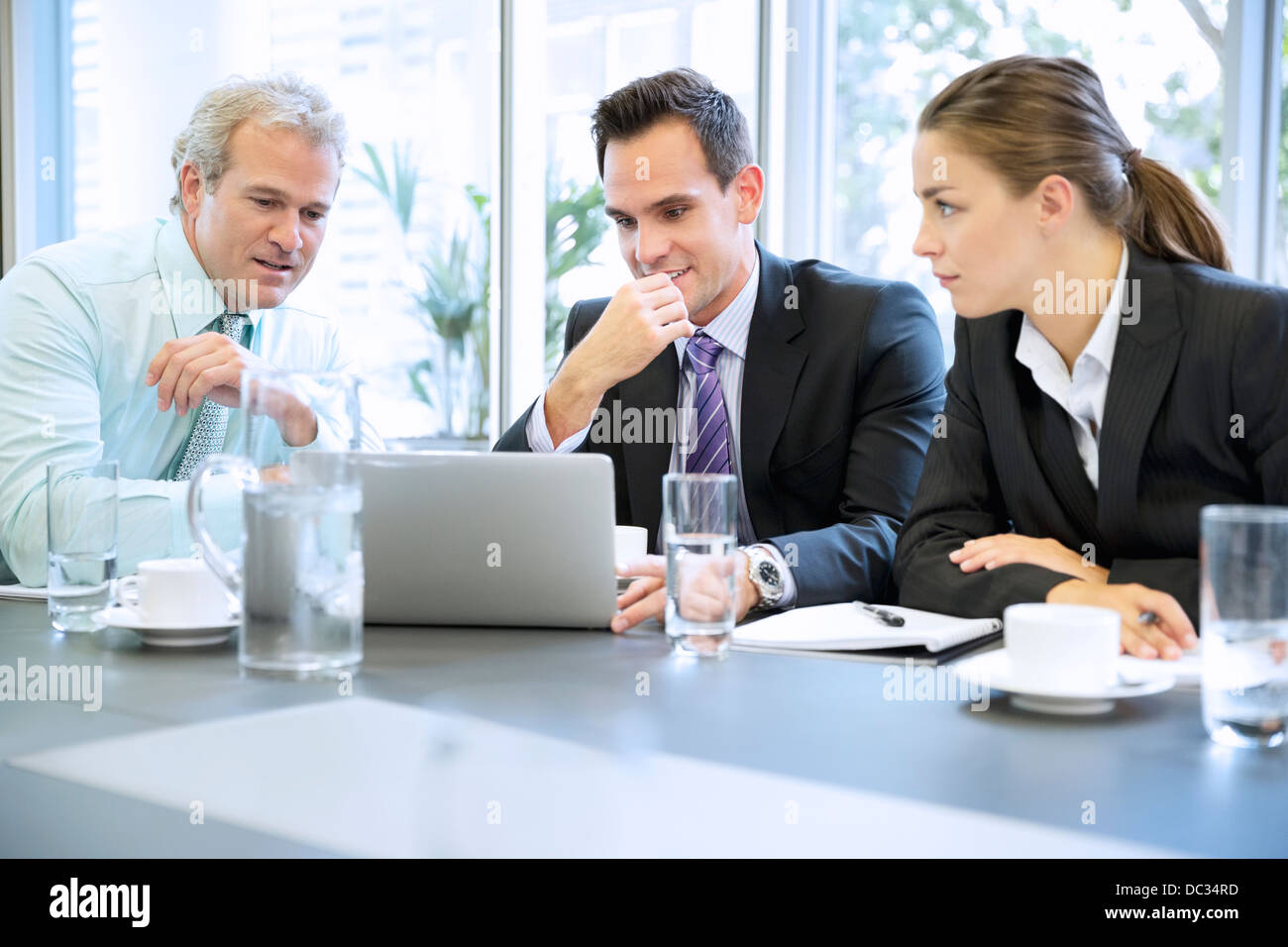 Business people sharing laptop in meeting Stock Photo - Alamy