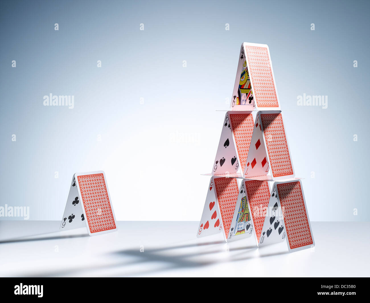Small house of cards next to large house of cards Stock Photo - Alamy