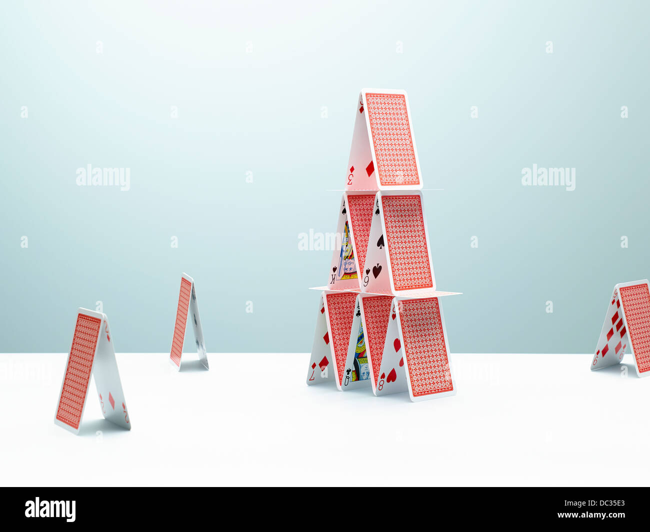 Small houses of cards surrounding large house of cards Stock Photo - Alamy