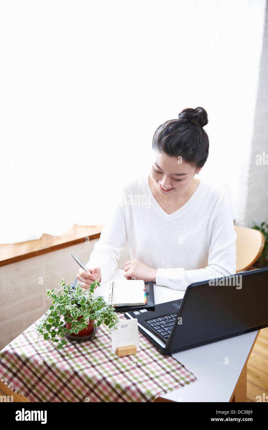 a woman working with a laptop on table Stock Photo - Alamy