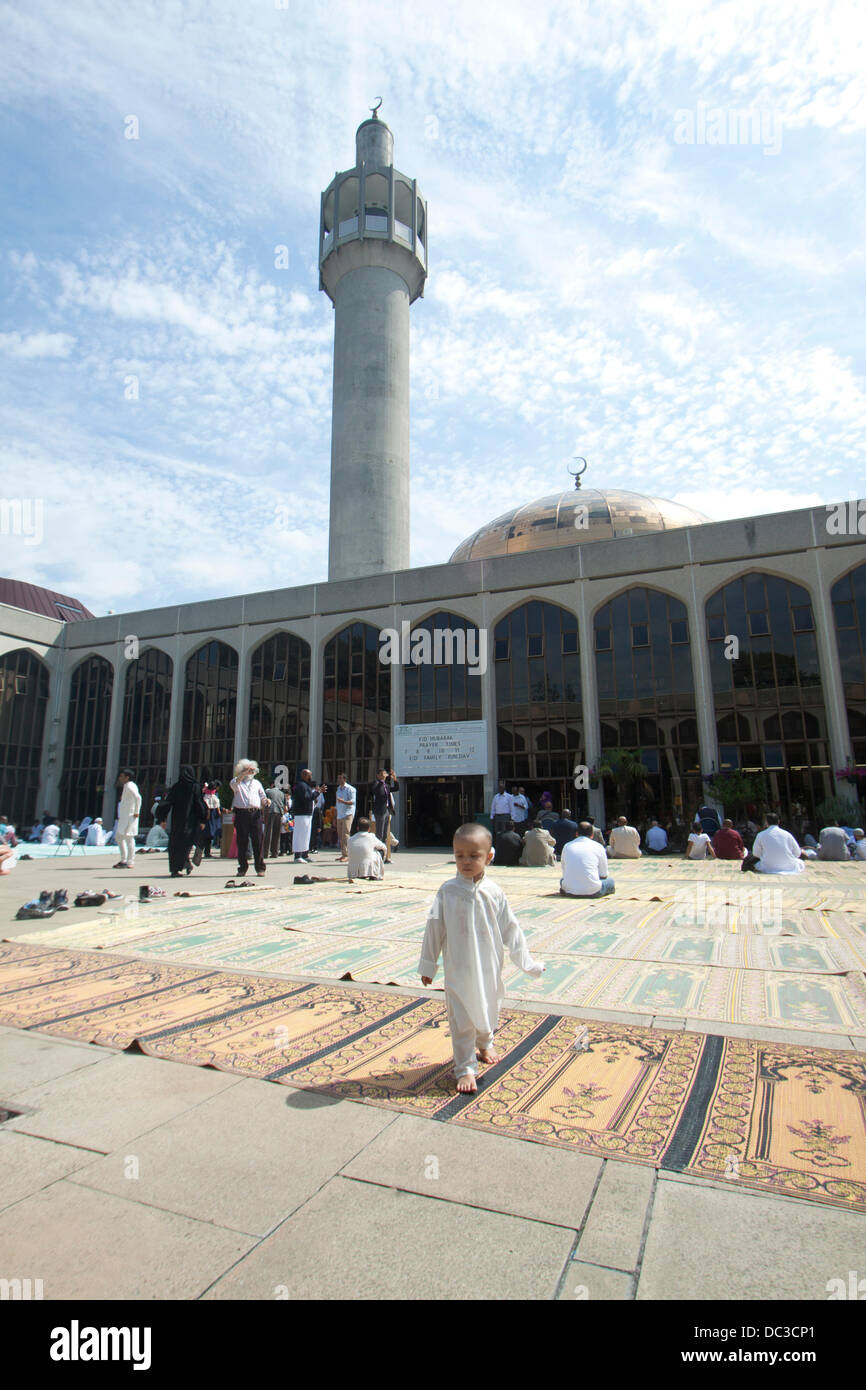London, UK. 8th August 2013. A Muslim boy walks on prayer matts at the ...