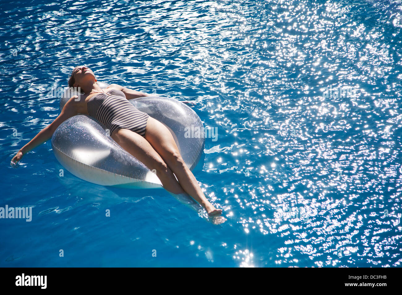 Carefree woman floating on inflatable ring in swimming pool Stock Photo - Alamy