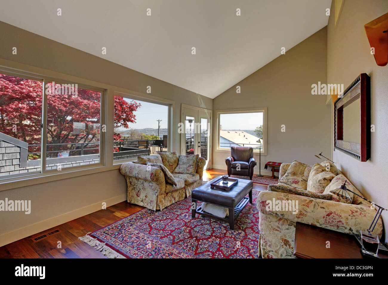 Living room with many windows and red rug Stock Photo - Alamy