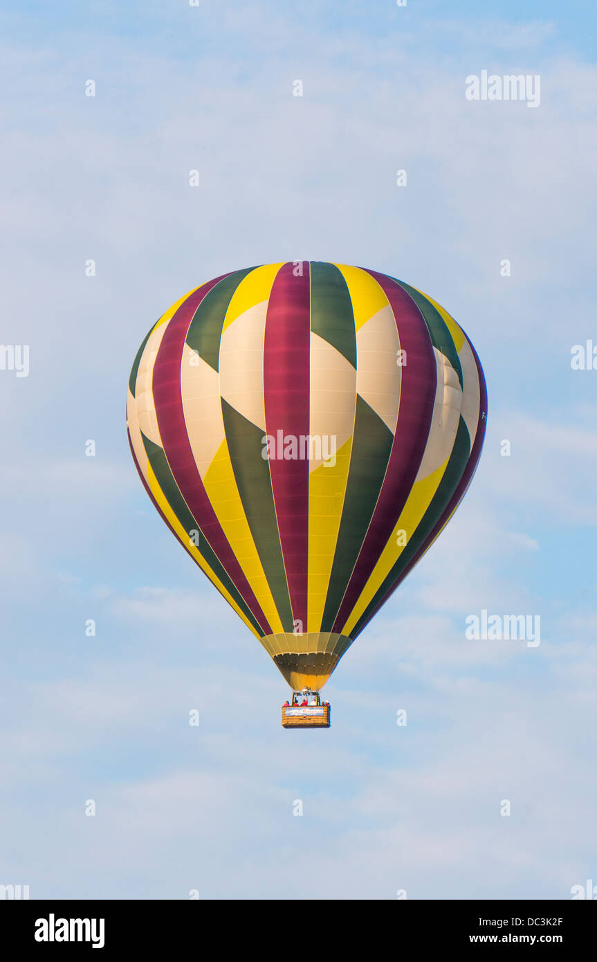 A hot air balloon with passengers, rising in the sky in calm conditions ...