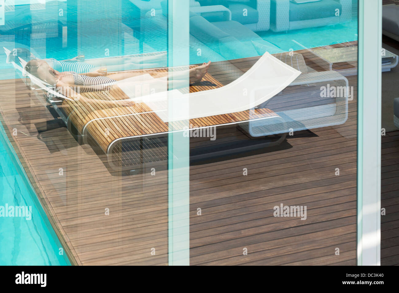 Woman sunbathing on lounge chair at luxury poolside Stock Photo - Alamy