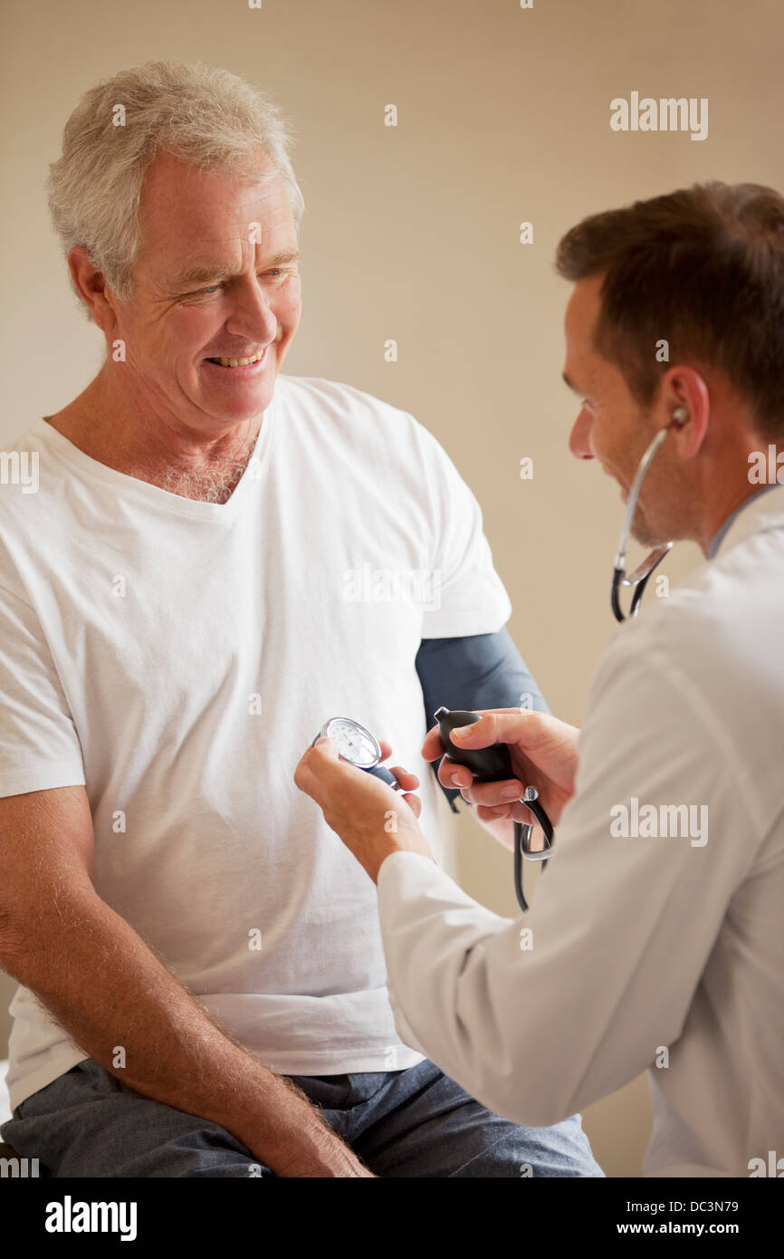Doctor checking senior man's blood pressure in doctor's office Stock ...