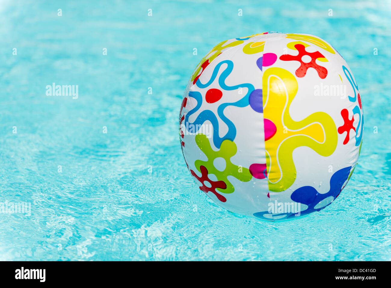 Colorful beach ball floating on water of swimming pool Stock Photo - Alamy